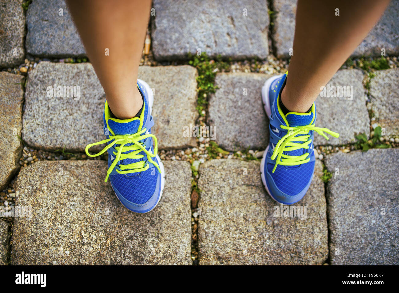 Female runner getting ready for training on tiled pavement in city ...