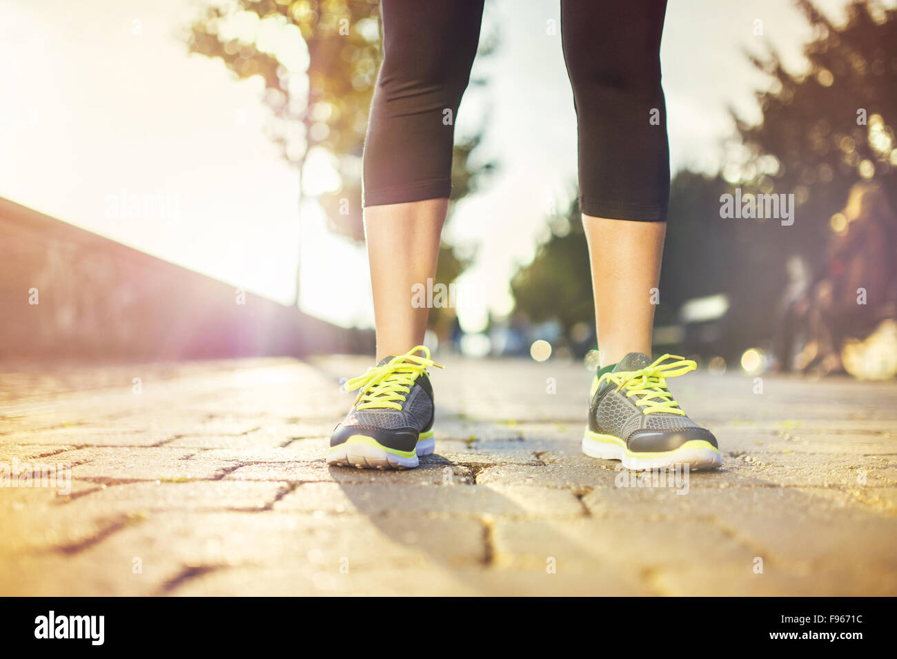Female runner running on tiled pavement in city quay, closeup on shoes ...