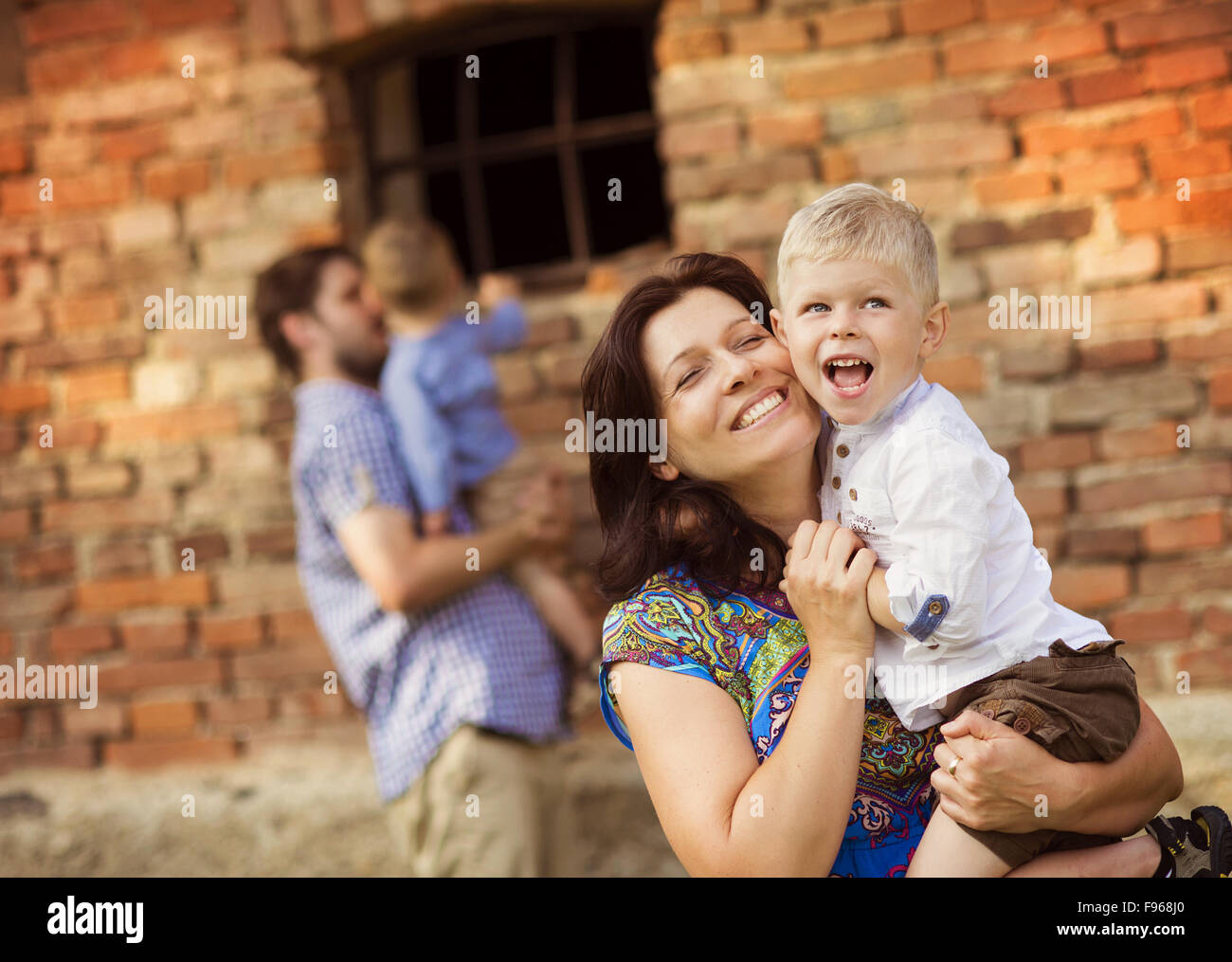 Happy young family have fun together in nature by the old brick house ...