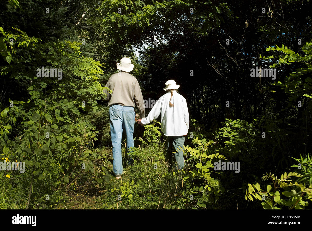 A couple walks in the woods behind their rural New England farm Stock ...