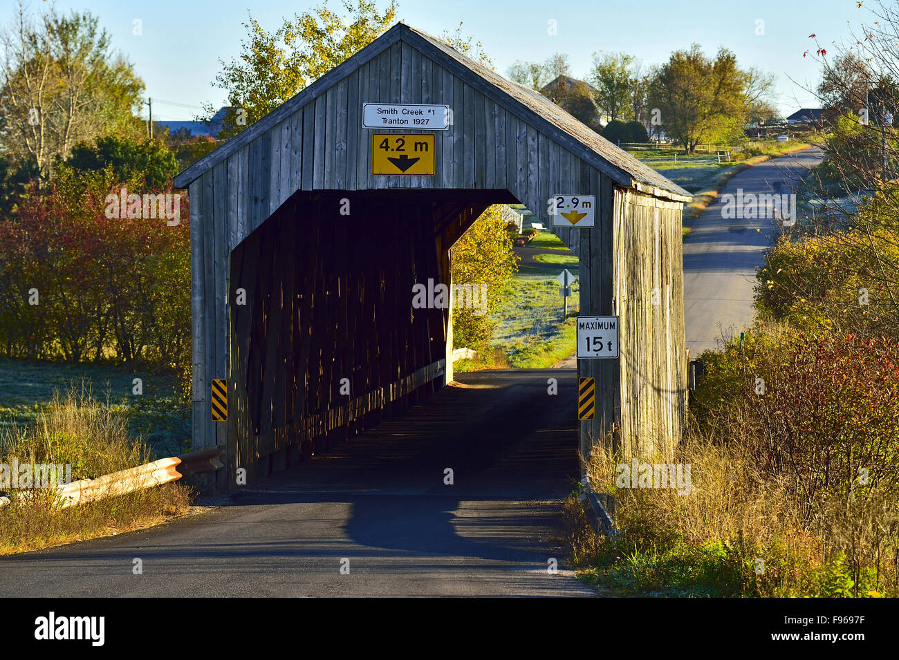 An autumn landscape image showing a one lane wooden covered bridge on a ...