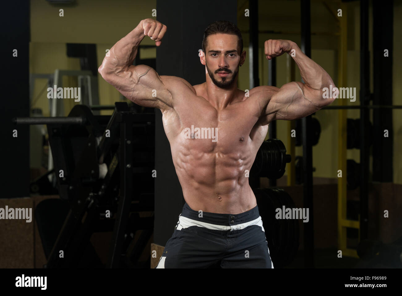 Serious Man Standing Strong In The Gym And Flexing Muscles Stock Photo ...