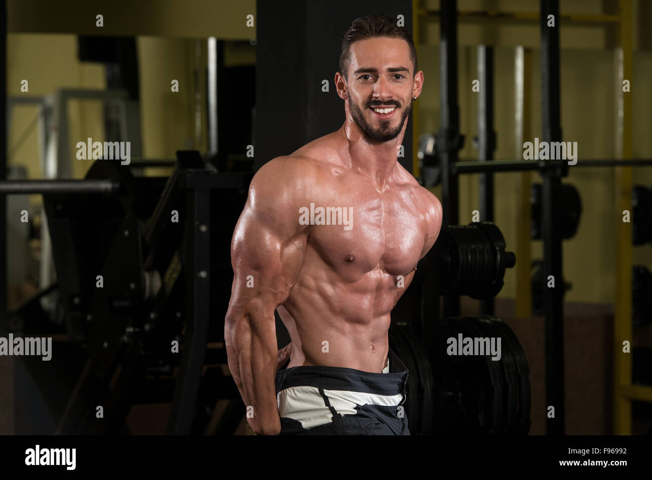 Serious Man Standing Strong In The Gym And Flexing Muscles Stock Photo ...