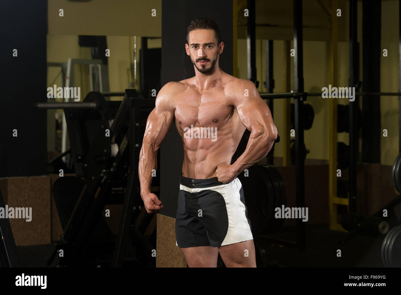 Serious Man Standing Strong In The Gym And Flexing Muscles Stock Photo ...
