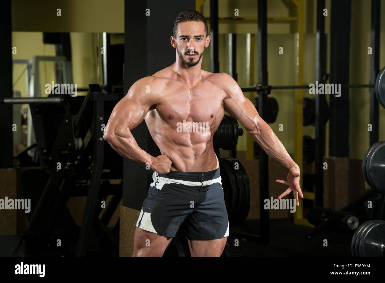 Serious Man Standing Strong In The Gym And Flexing Muscles Stock Photo ...