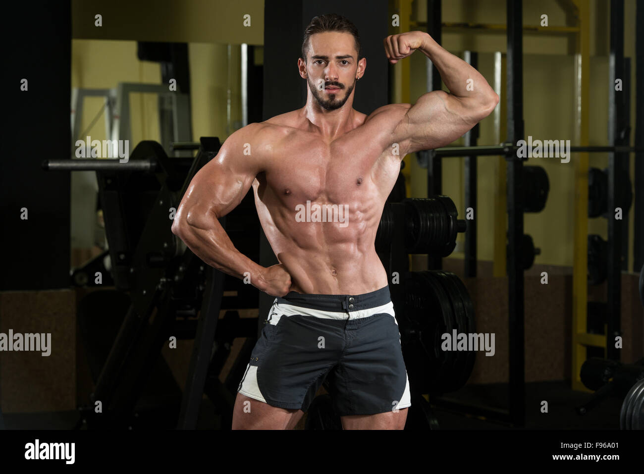 Serious Man Standing Strong In The Gym And Flexing Muscles Stock Photo ...