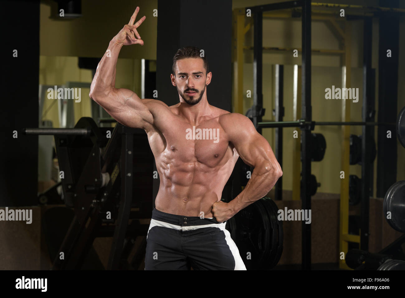 Serious Man Standing Strong In The Gym And Flexing Muscles Stock Photo ...