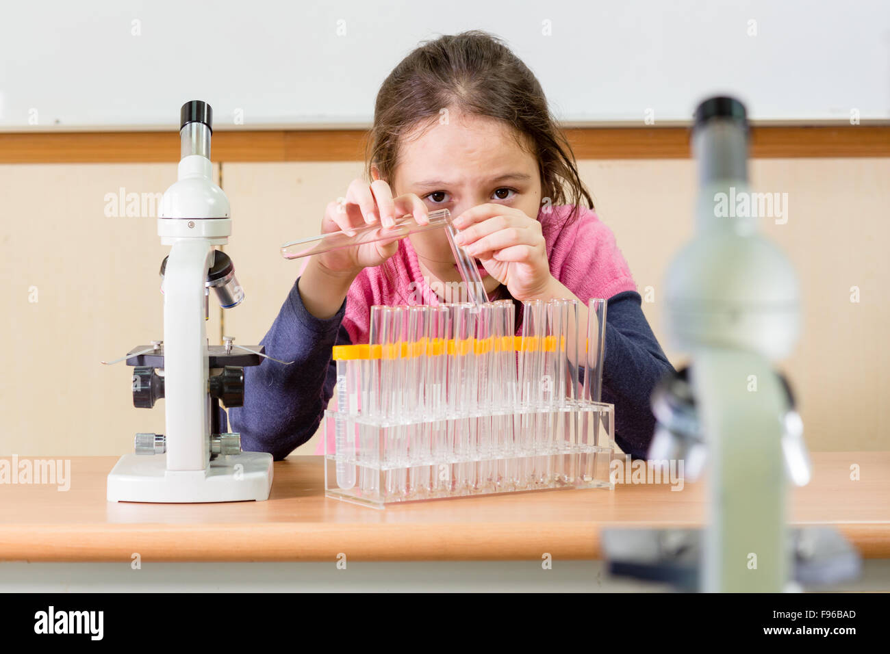 Young girl scientist with microscope and test tubes in science lab ...