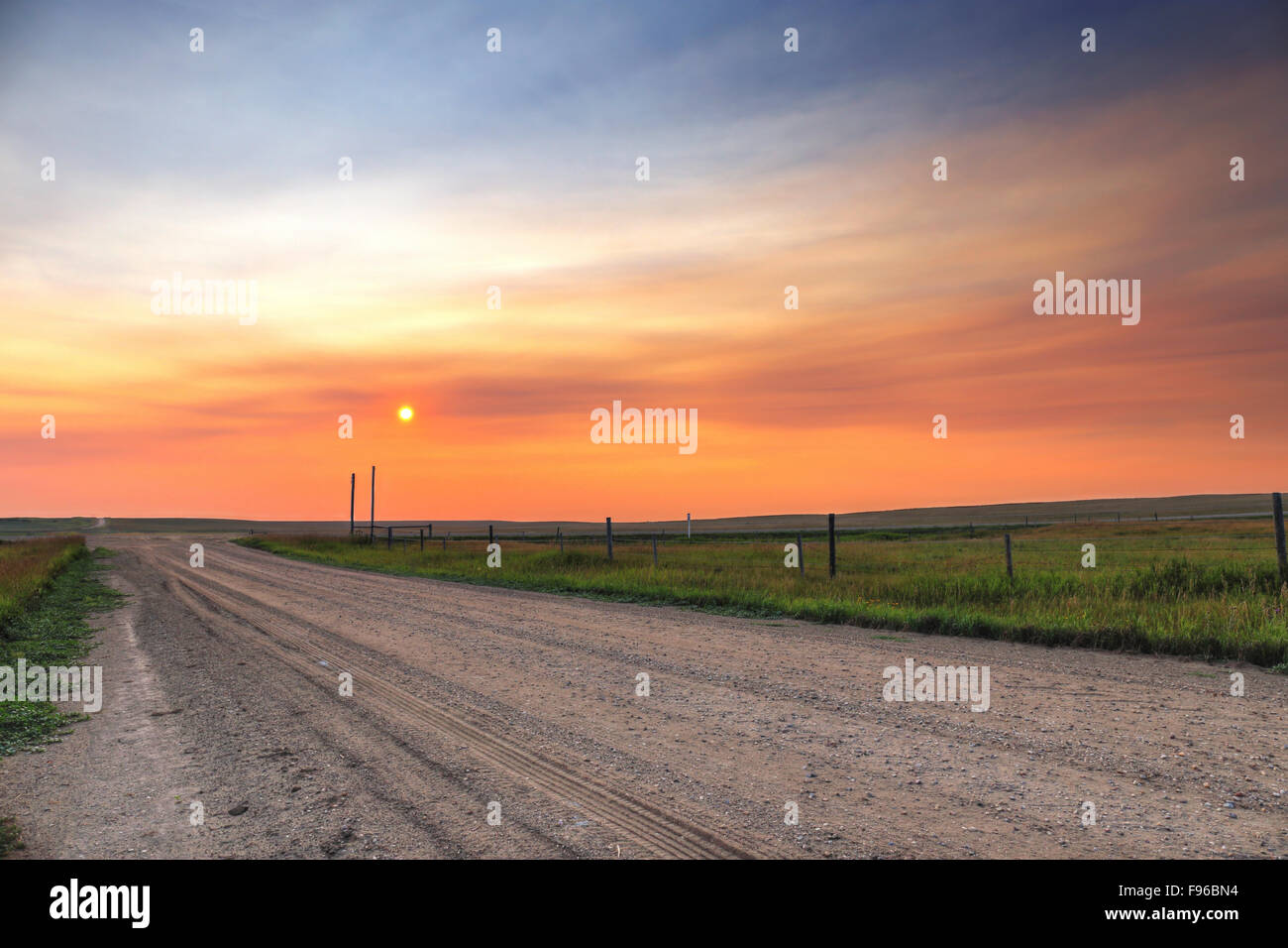 sunset, southern Saskatchewan, prairie, gravel road, fenced pasture ...