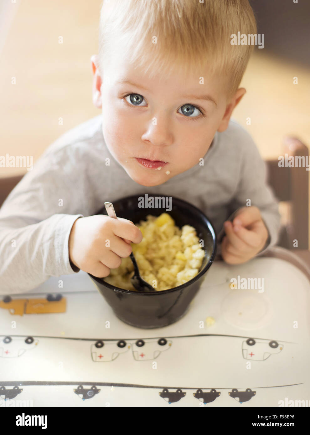 Cute little blonde boy eating pasta from black bowl Stock Photo - Alamy