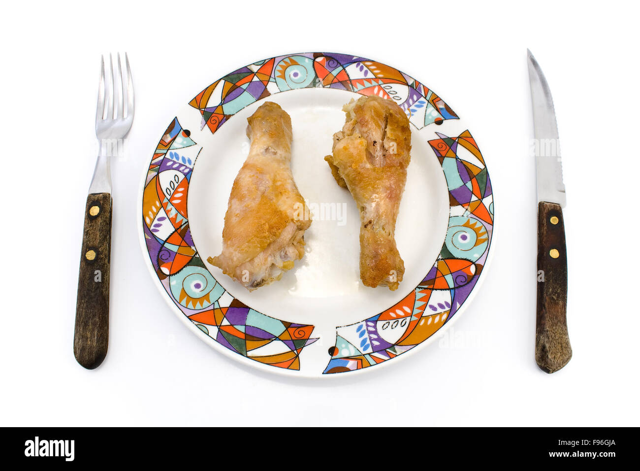 Roasted chicken legs on plate with fork and knife isolated on white ...