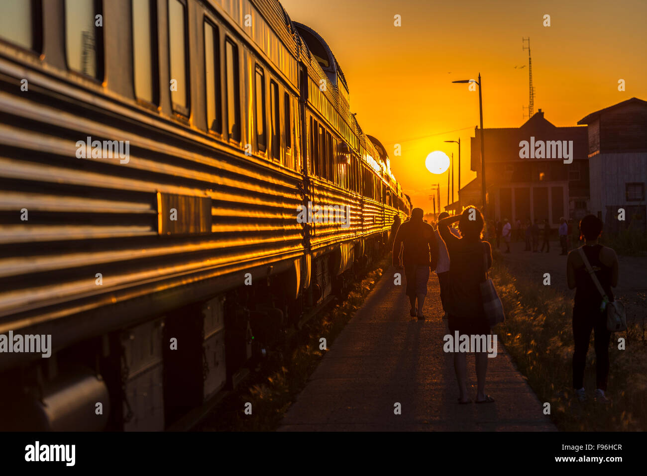 Sun setting in front of passenger train stopped in the town of Melville ...