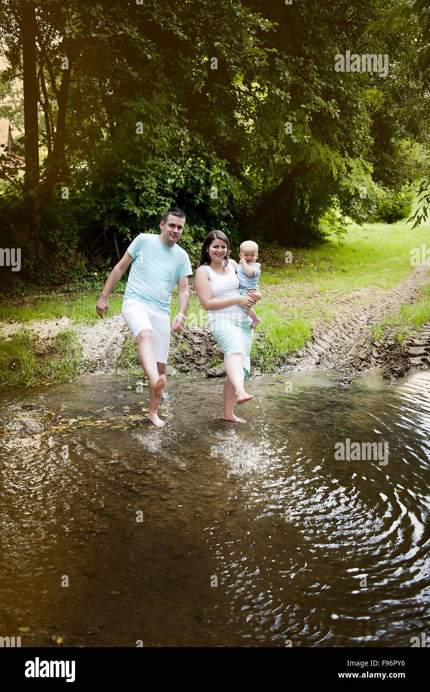 Happy family with little baby boy is splashing water in the river Stock ...