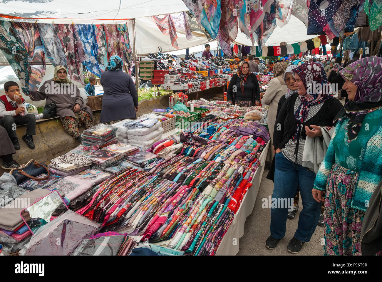 Two women with traditional clothes buy colorful kerchiefs in the open ...