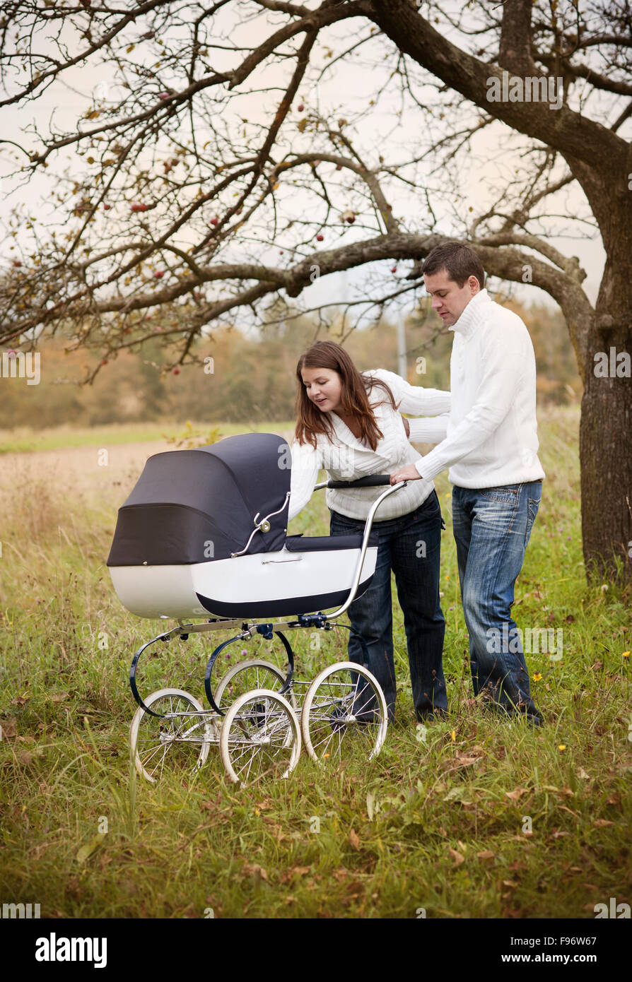 Happy and young family with vintage pram relaxing together in golden ...