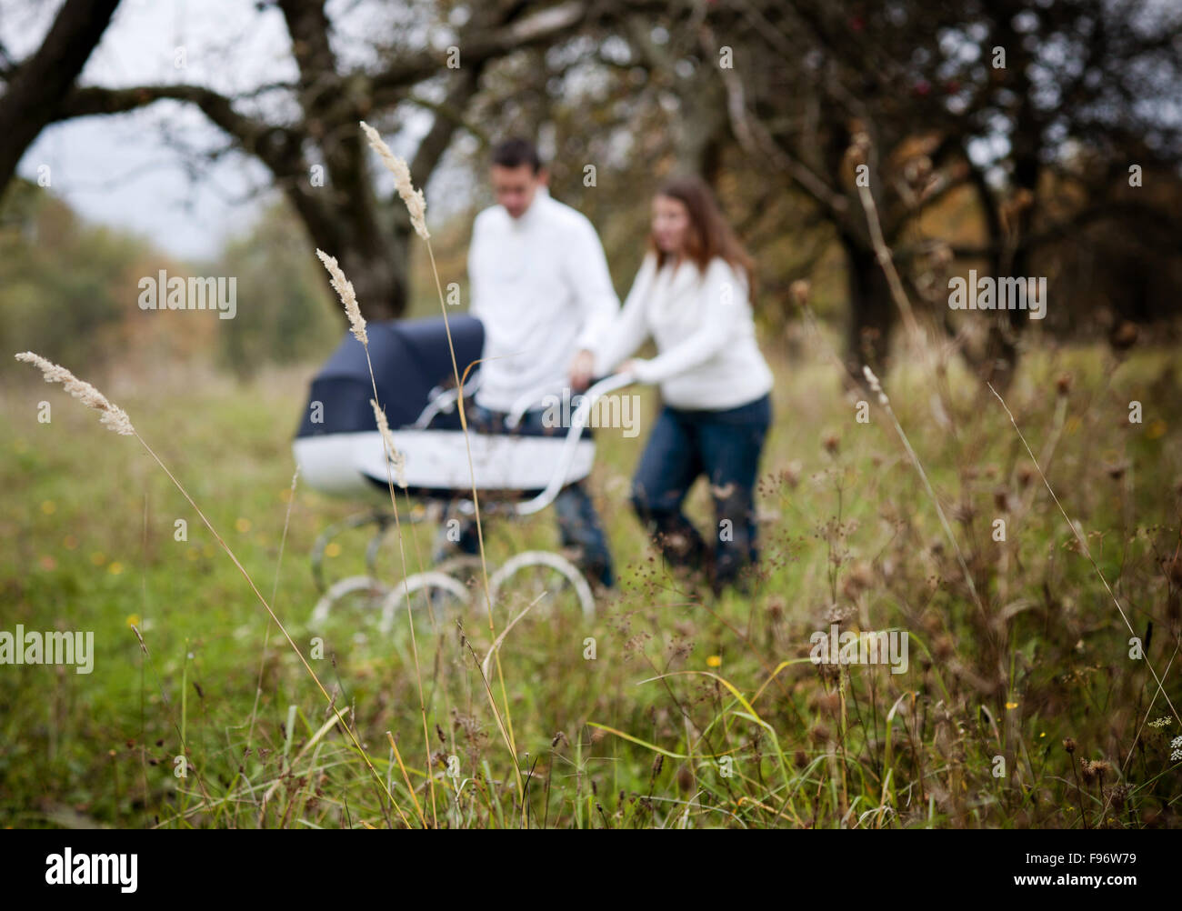 Happy and young family with vintage pram relaxing together in golden ...