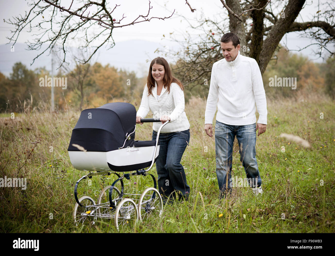 Happy and young family with vintage pram relaxing together in golden ...