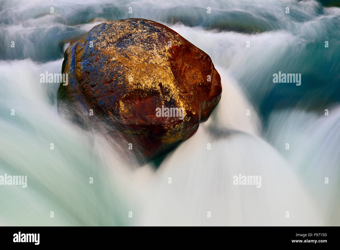 A horizontal landscape image of a big rock surrounded by the rushing ...