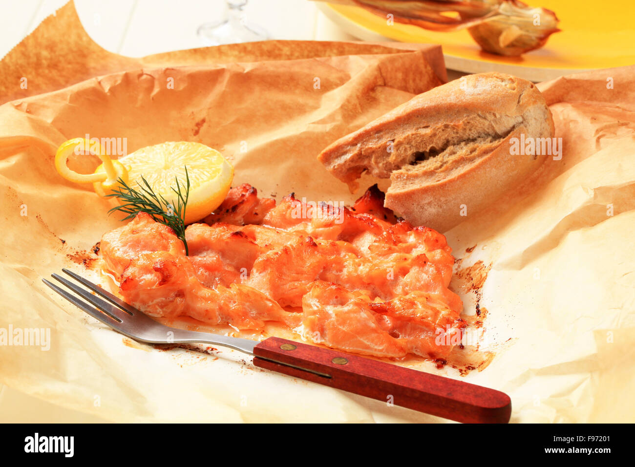 Salmon in parchment with lemon and bread roll Stock Photo - Alamy