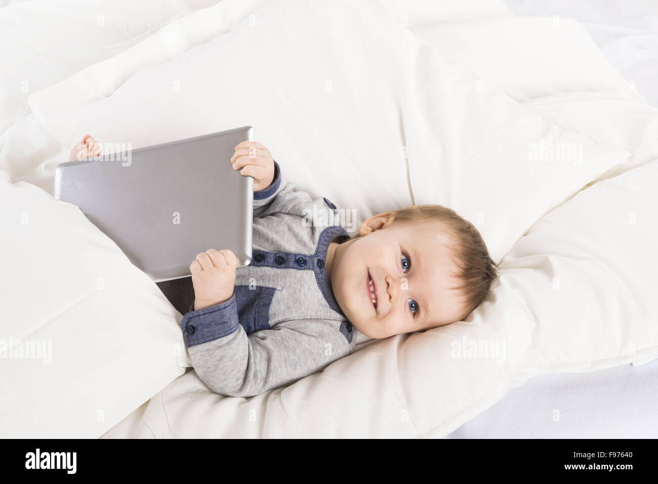 Baby with digital tablet is playing in the bed Stock Photo - Alamy