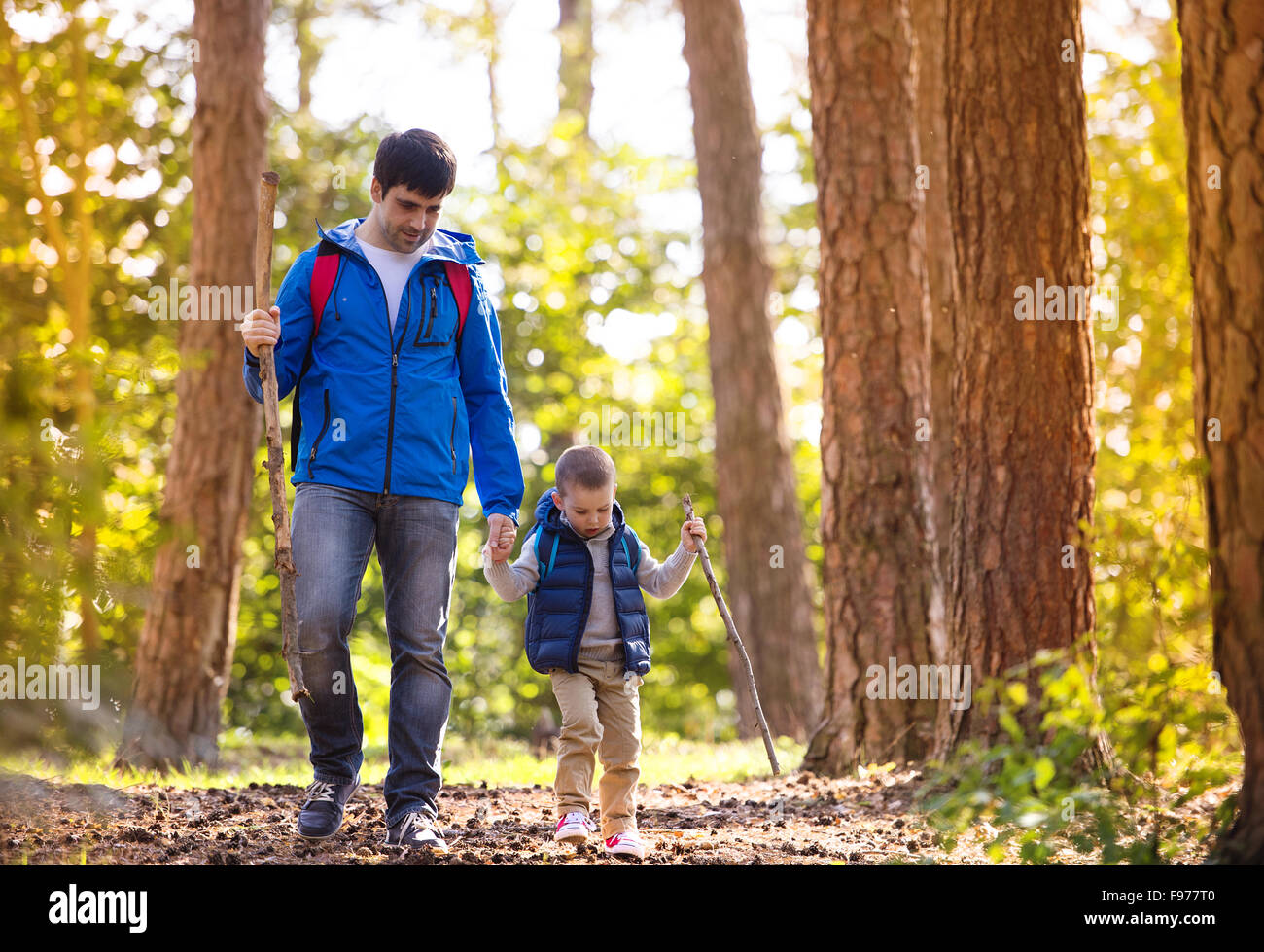 Father And Son Walking During The Hiking Activities In Autumn Forest At