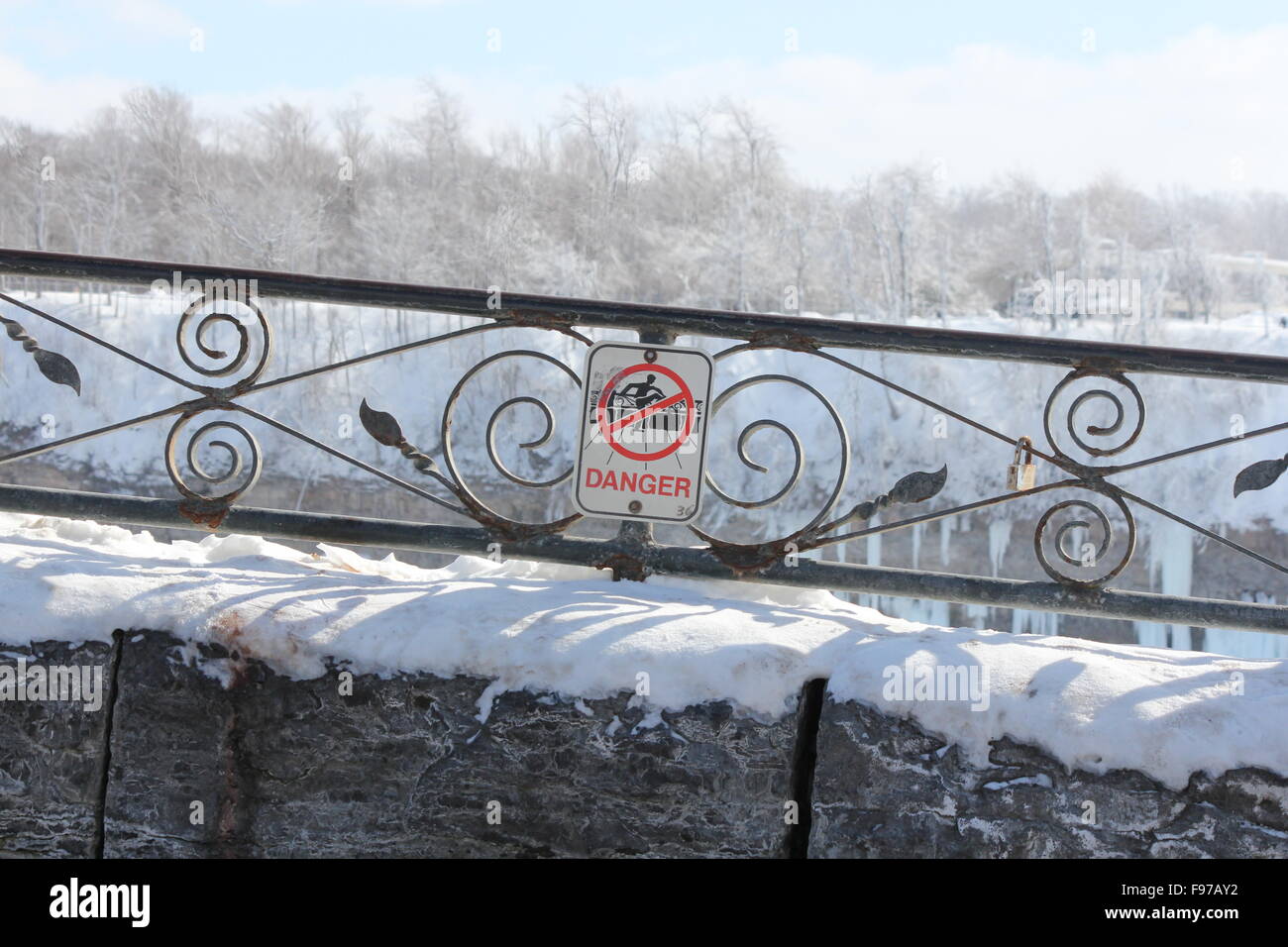 Sign posted on retaining wall warning of danger of climbing railing ...
