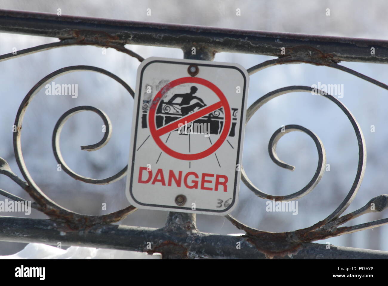 Sign posted on retaining wall warning of danger of climbing railing ...