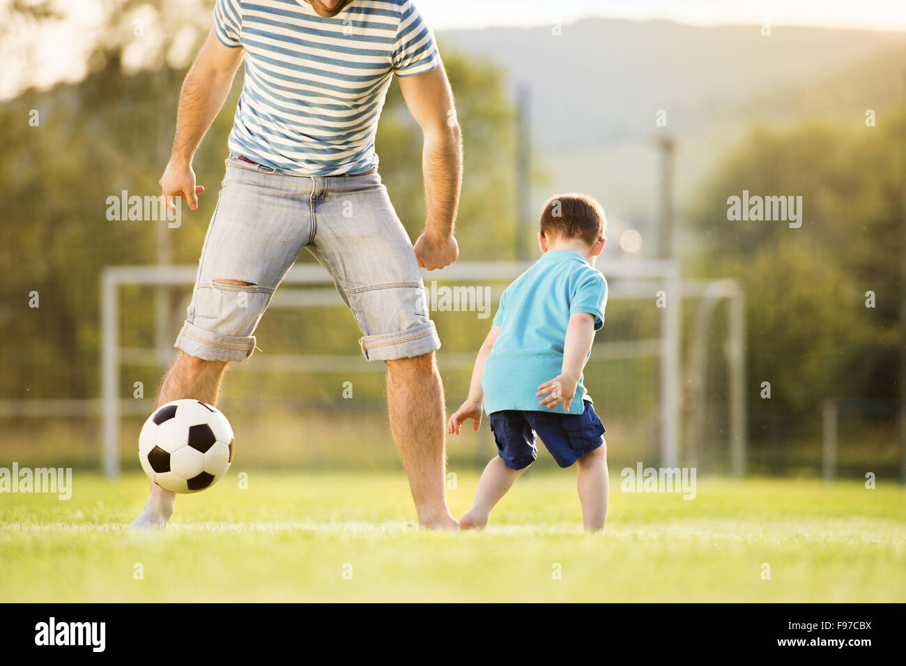 Young father with his little son playing football on football pitch ...