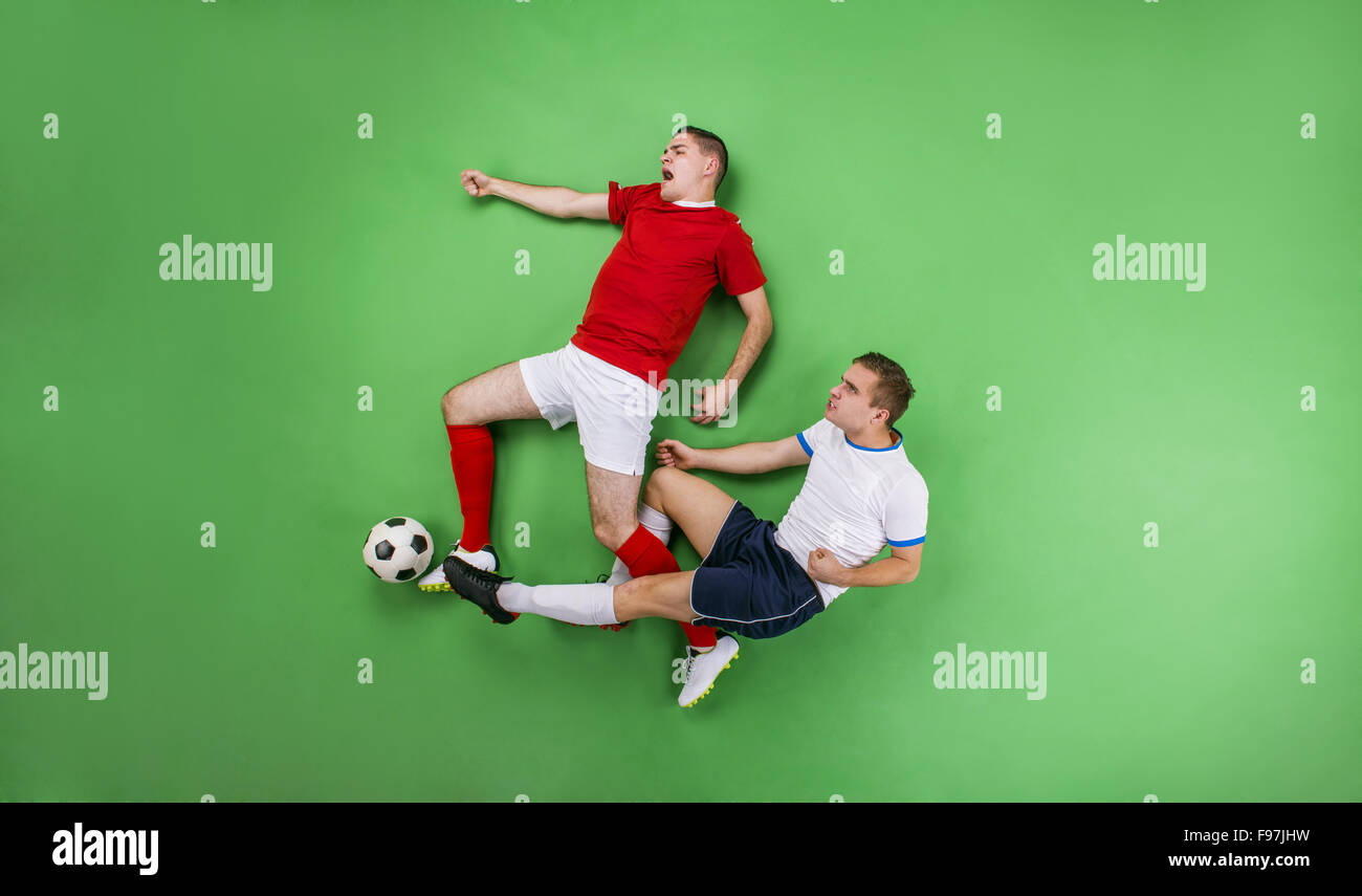 Two enthusiastic football players fighting for a ball. Studio shot on a ...