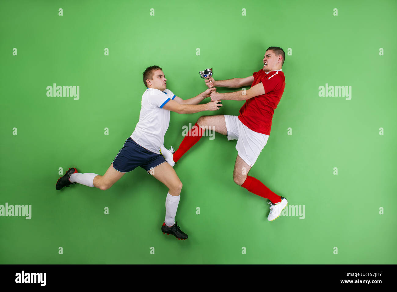 Two enthusiastic football players fighting for a trophy. Studio shot on ...