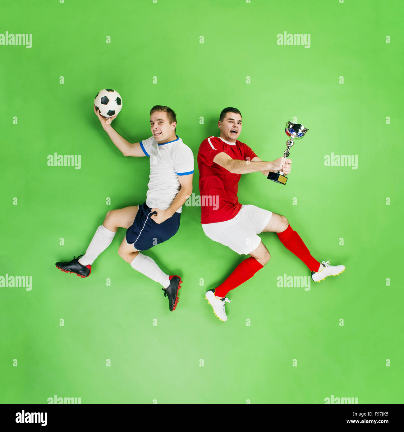 Two football players celebrating victory. Studio shot on a green ...