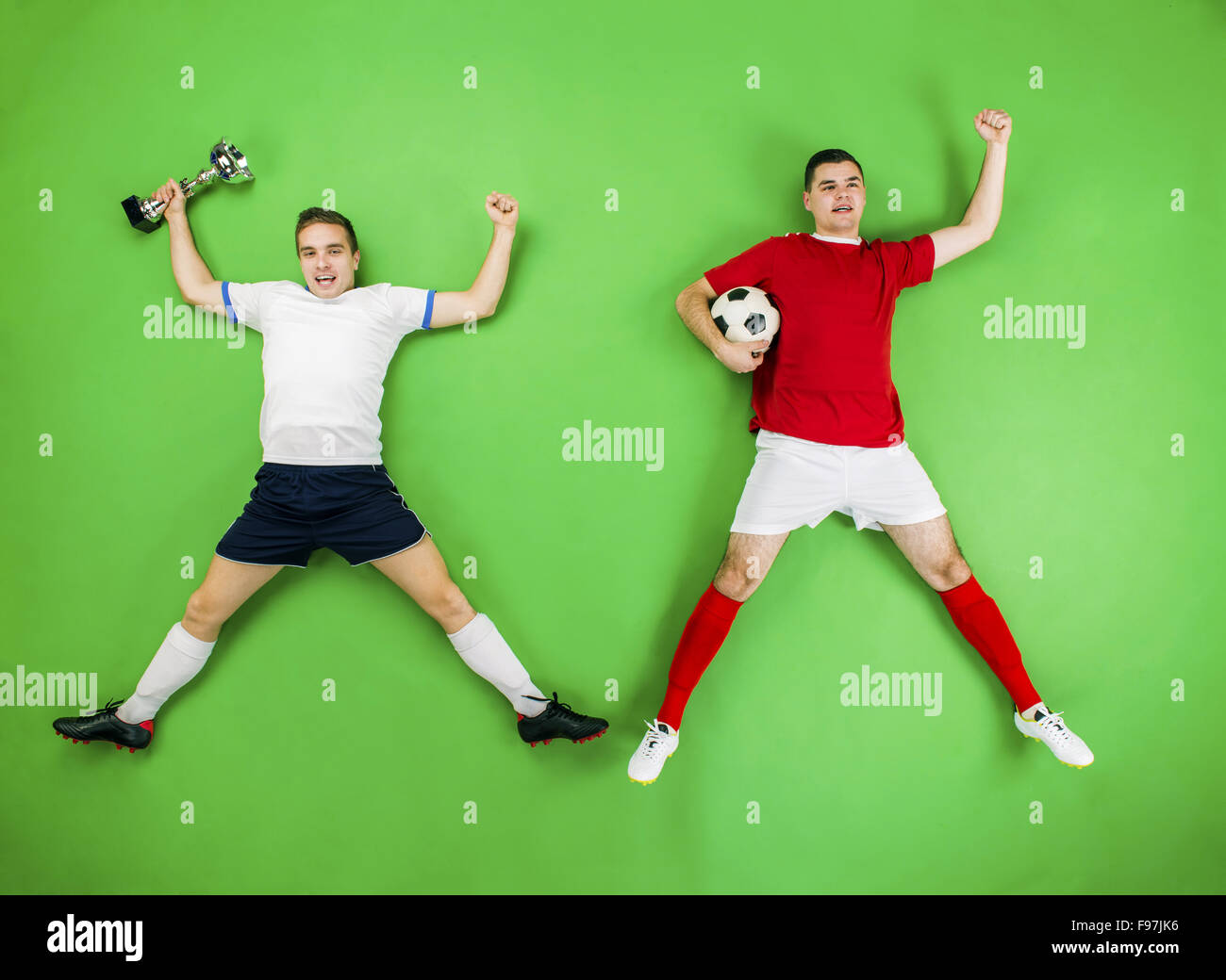 Two football players celebrating victory. Studio shot on a green ...