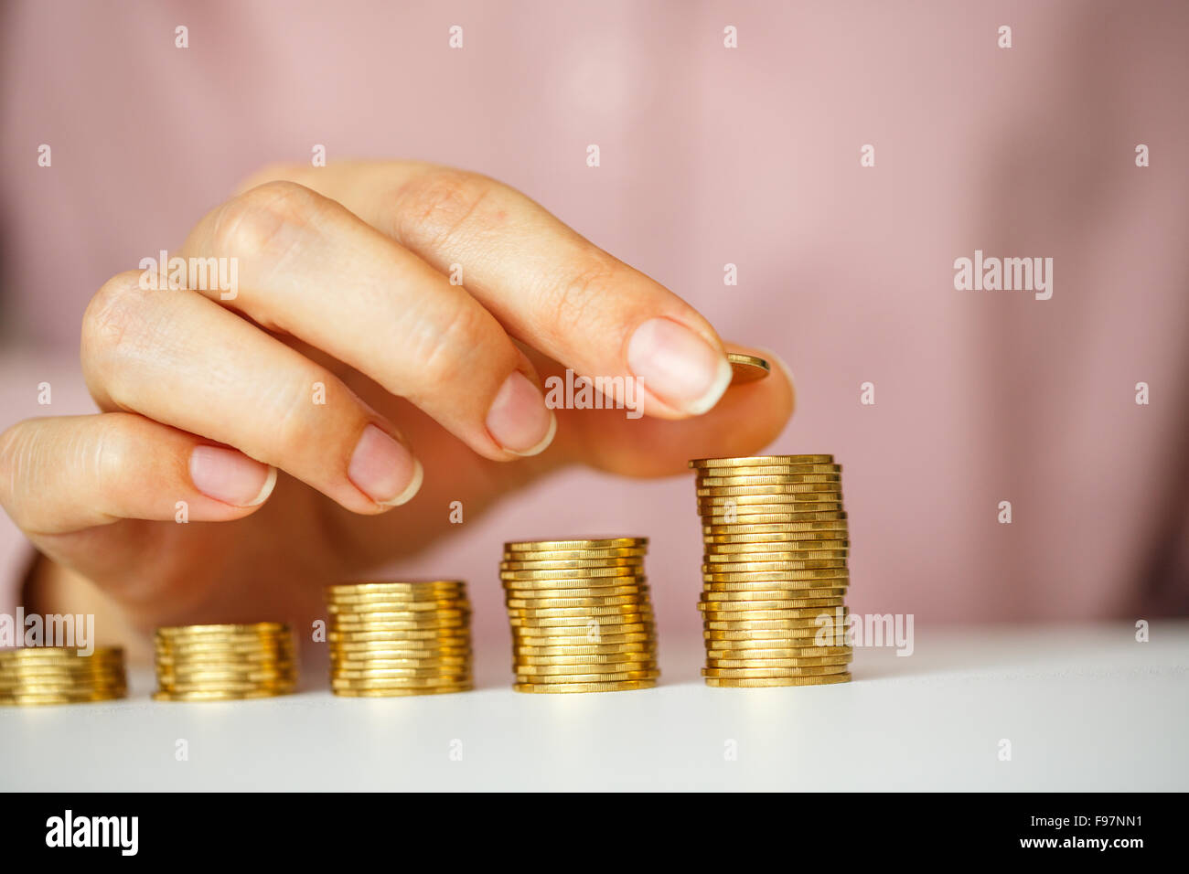 Savings, female hand stacking gold coins into increasing columns Stock ...