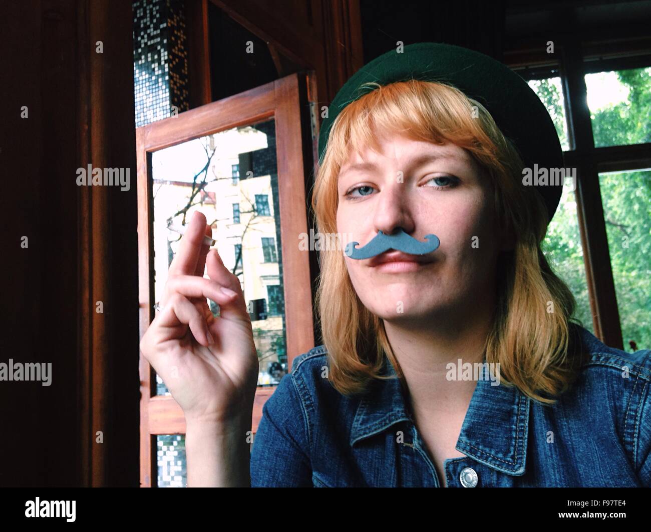 Portrait Of Young Woman Wearing Artificial Mustache While Smoking ...