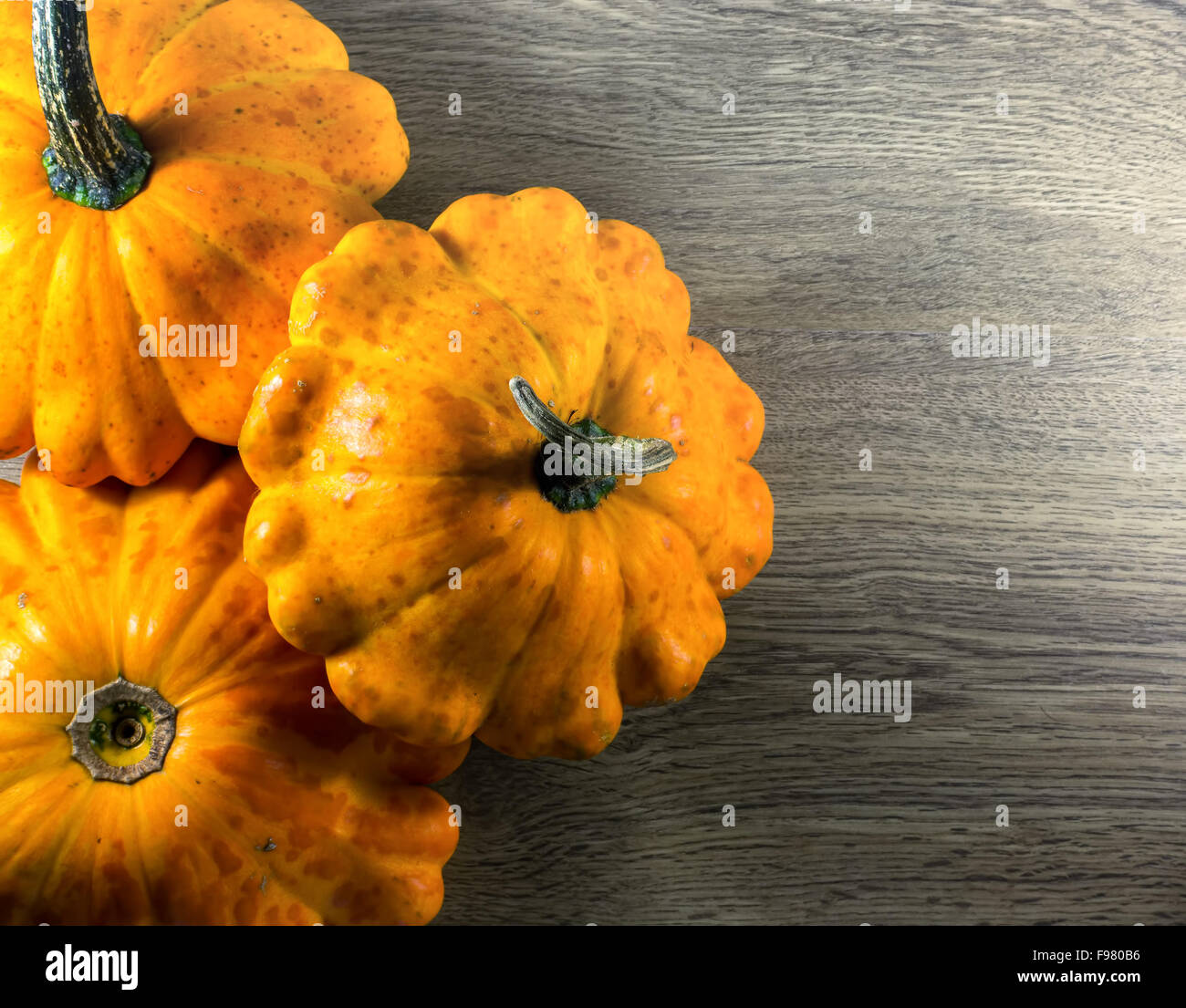 Three small ripe orange pumpkins on a natural rustic wood background ...