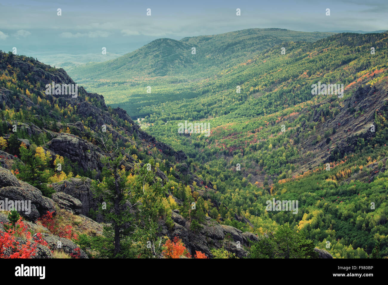 Large rocks and forests create a rugged landscape with dramatic sky ...
