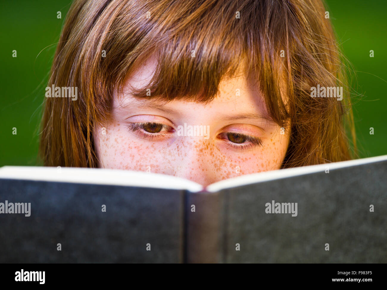 Young beautiful girl reading a book outdoor Stock Photo - Alamy