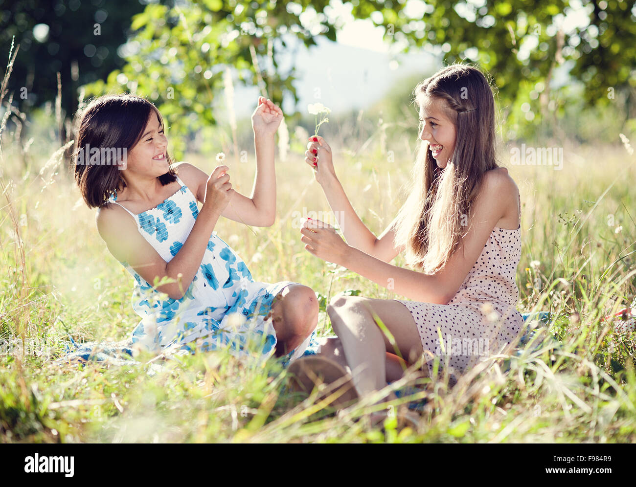 Two sisters laughing and playing in green sunny park Stock Photo - Alamy