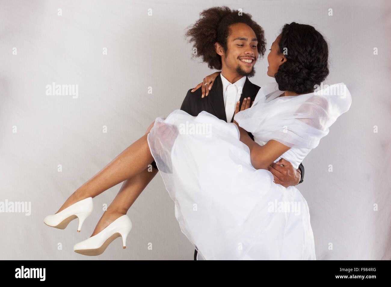 Romantic Black couple, she in a wedding dress and he holding her Stock ...