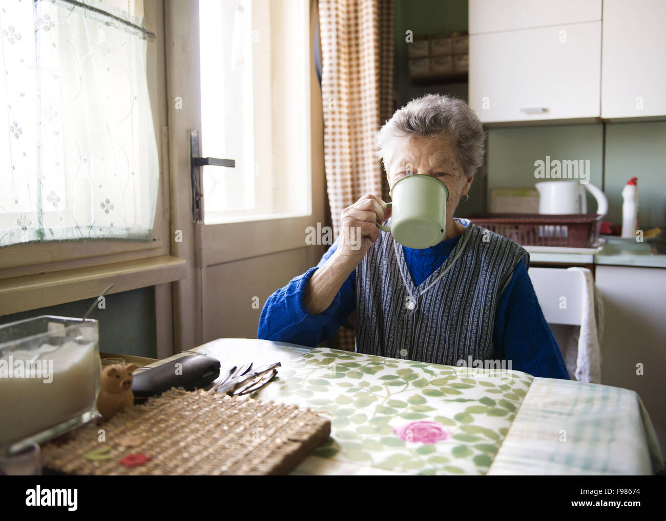Old woman is drinking tea in her country style kitchen Stock Photo - Alamy