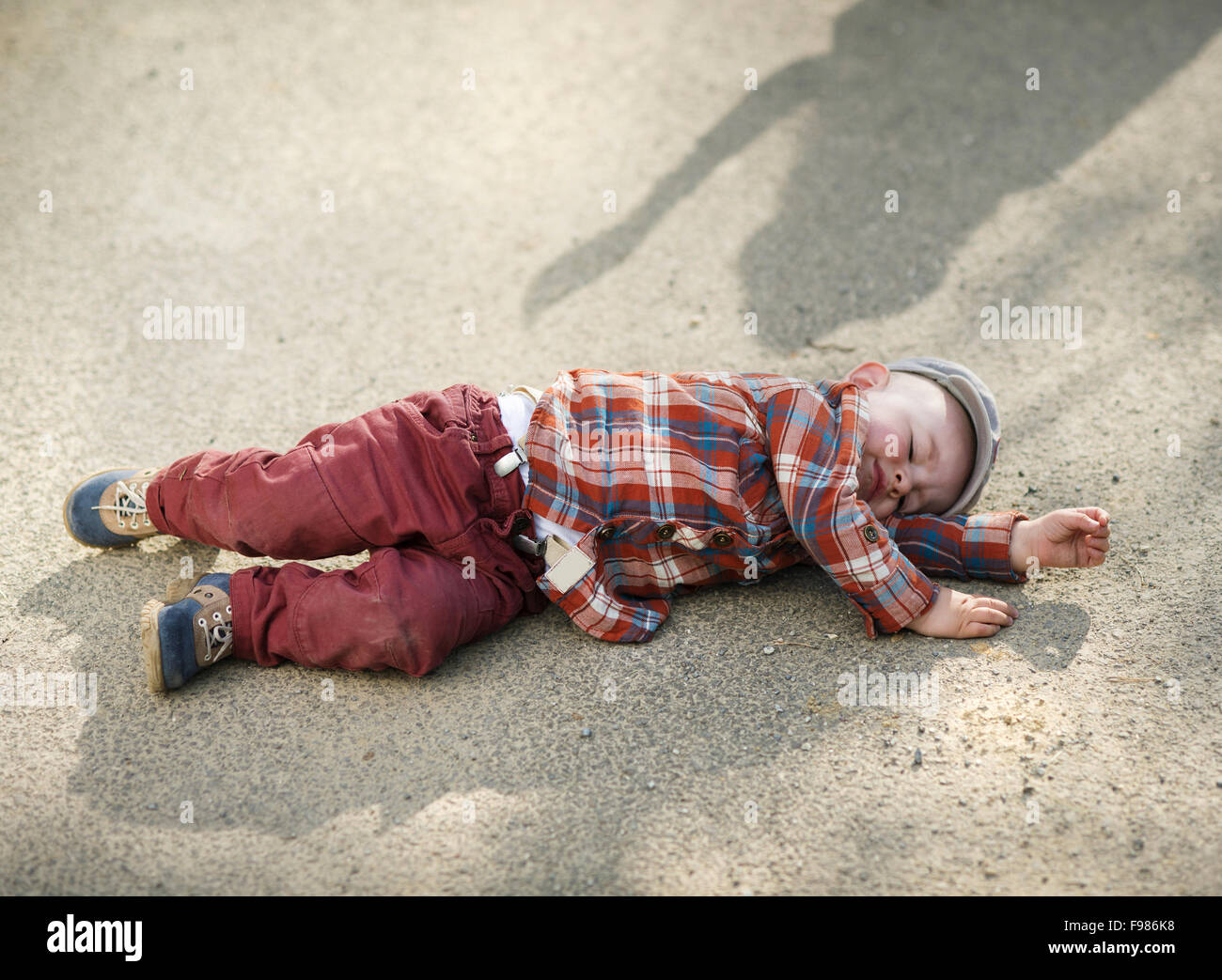 Outdoor portrait of little boy crying and lying down on the sidewalk ...