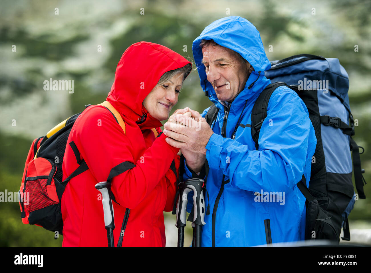 Senior tourist couple hiking at the beautiful mountains in cold weather ...