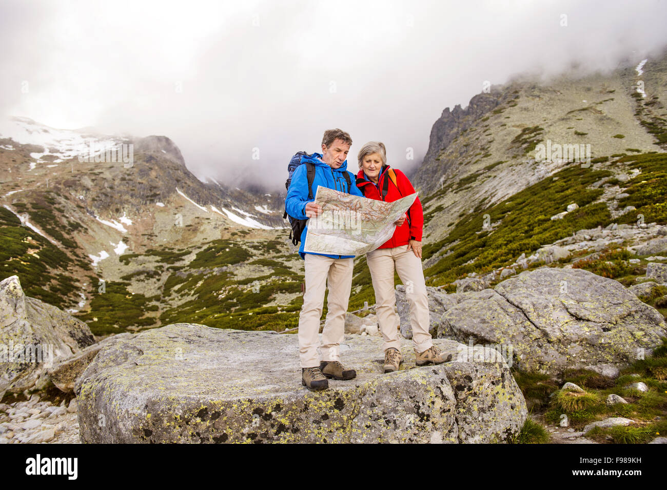 Senior hikers couple looking at the hike map during the hike in ...