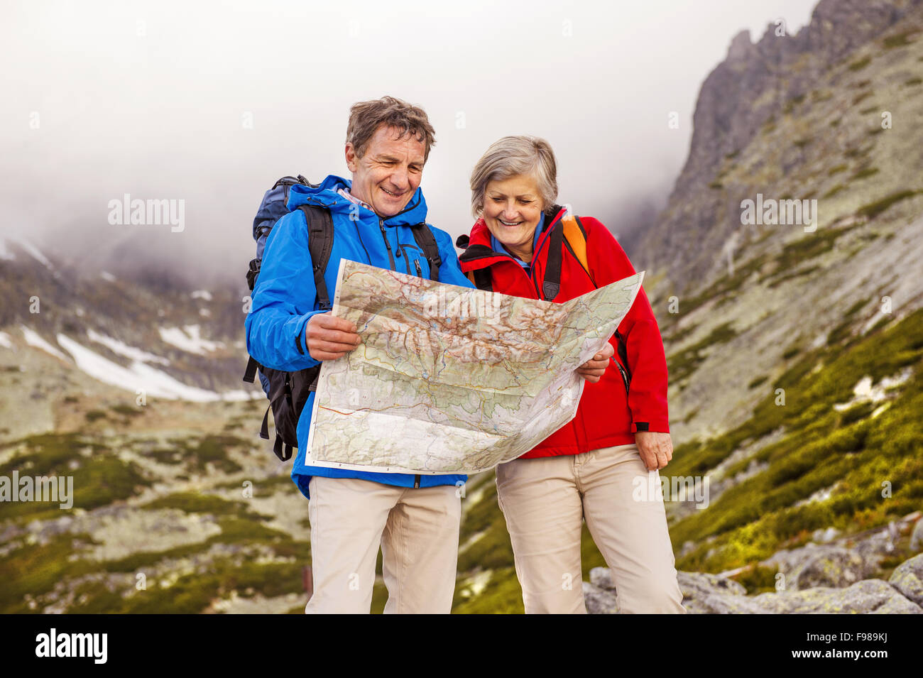 Senior hikers couple looking at the hike map during the hike in ...