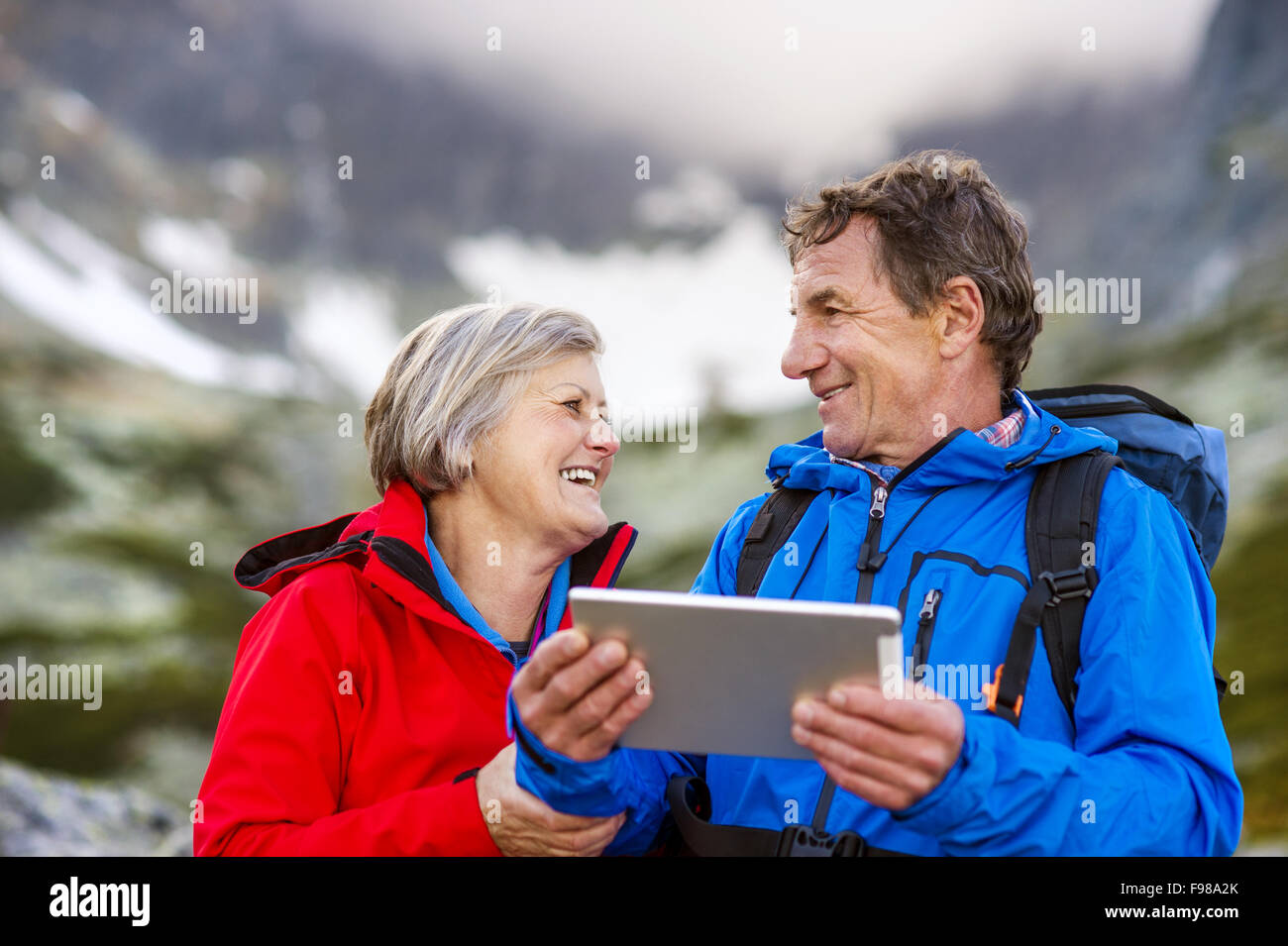 Senior hiking couple using travel app or map on tablet during the hike ...