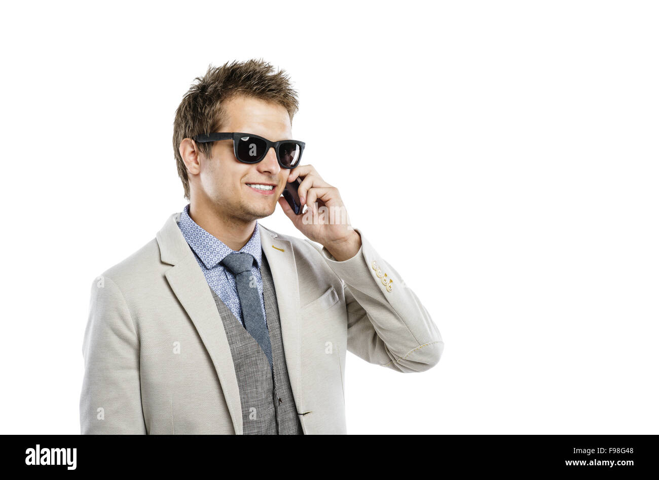 Studio shot of young modern businessman in sunglasses making a phone ...