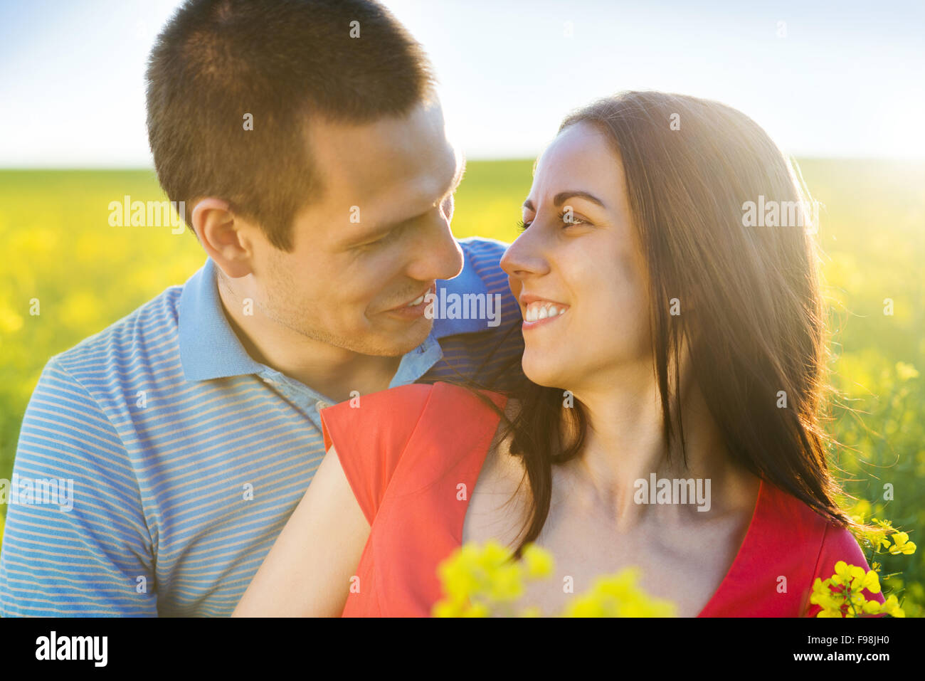 Happy young couple in love hugging in yellow colza field Stock Photo ...