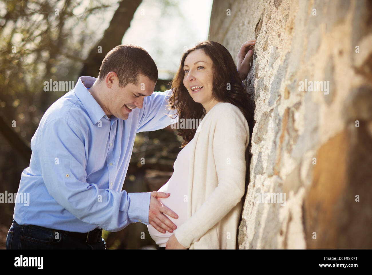 Happy young pregnant couple hugging in nature Stock Photo - Alamy