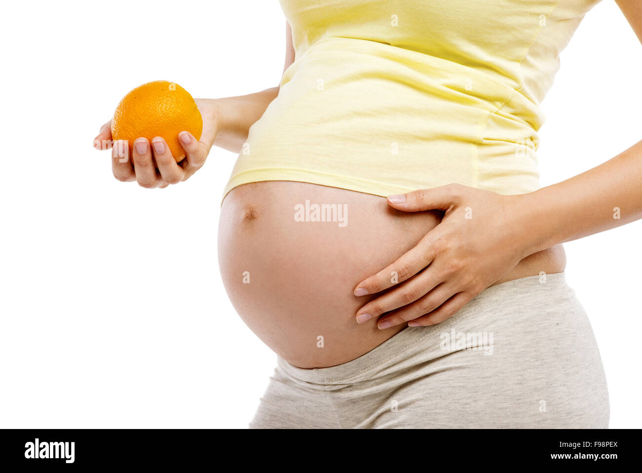 Unrecognizable pregnant woman holding orange, isolated on white ...