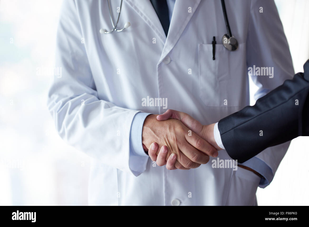 doctor handshake with a patient at doctors bright modern office in ...
